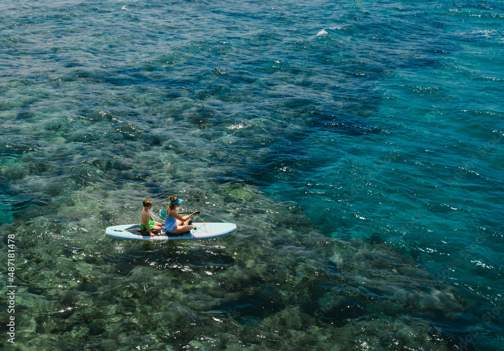 Mom and son stand up paddle boarding over ocean coral reefs Stock Photo ...