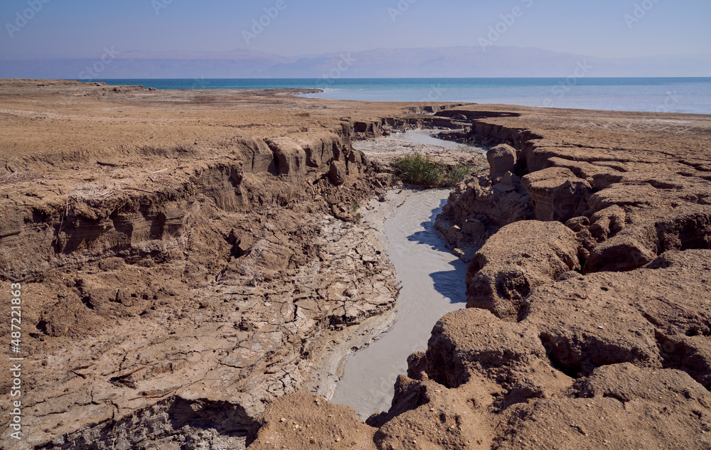 Dirty stream flowing into the Dead Sea. Erosion of the coastline ...