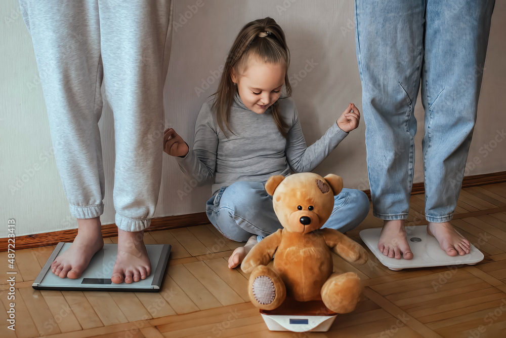 The family is weighed at home, two young women stand on the scales, a ...