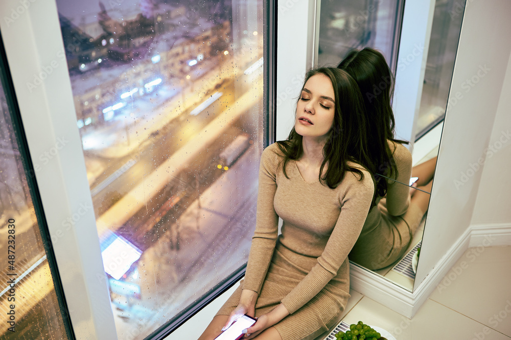 Floor to ceiling window with 20 years old woman with closed eyes and ...