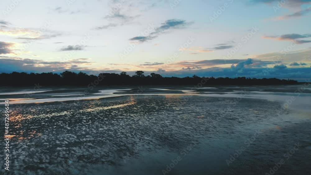 Slow push towards the treeline over an amazingly reflective beach from ...