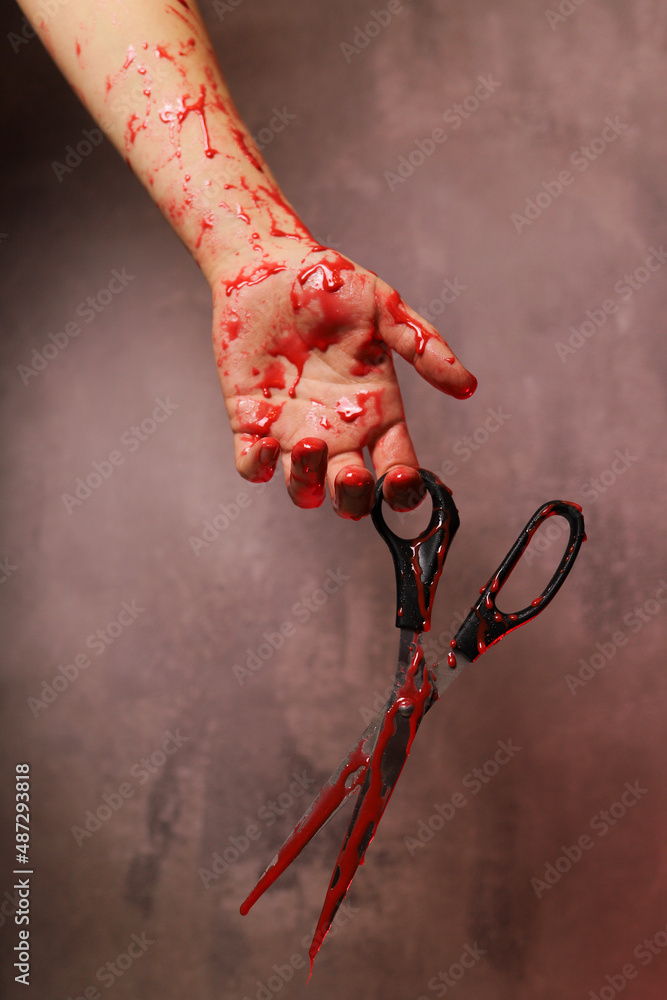 bloody hand holding big bloody scissors on a gray background, the ...