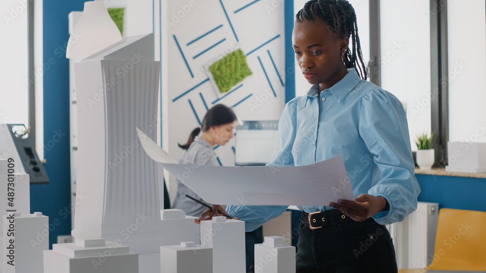 Close up of woman engineer analyzing blueprints plan and building model ...
