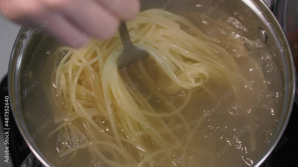 italian cuisine, delicious spaghetti is boiled in boiling water in a ...