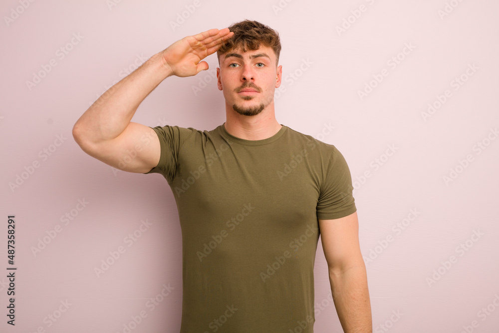 young cool man greeting the camera with a military salute in an act of ...