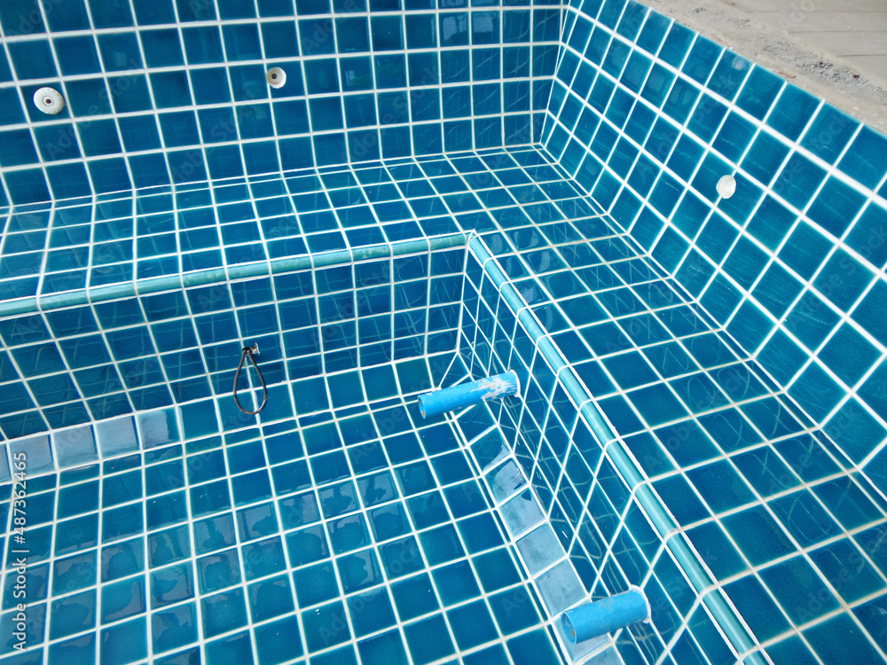Tiled pool. The man hand while using spacer for installing tiles ...