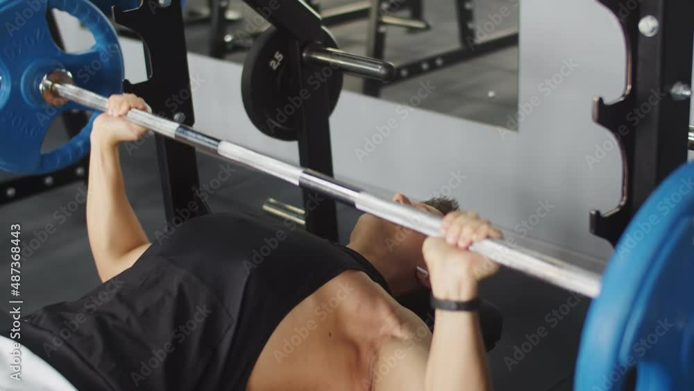 Male bodybuilder trains in gym with barbell in prone position on bench ...