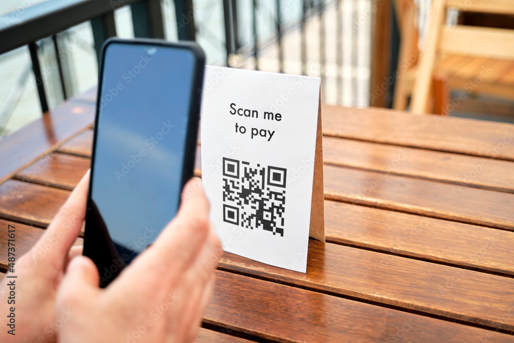Unrecognizable client scanning a QR code to pay cashless, contactless ...