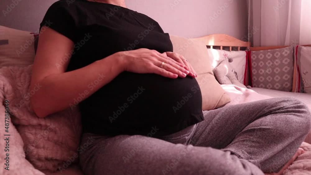 A Caring Mother Strokes A Pregnant Tummy With Two Hands On Light Room