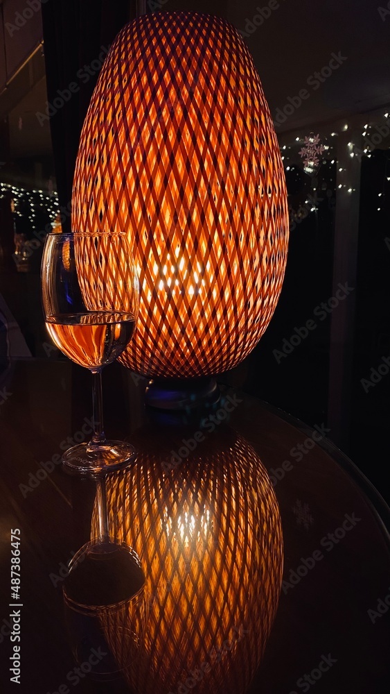 Lampshade and reflection on glass in modern living room at night ...