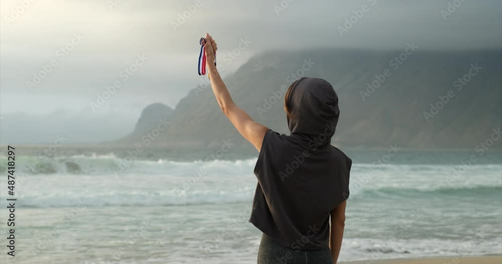 woman hand raised, holding gold medal against sky. female athlete ...
