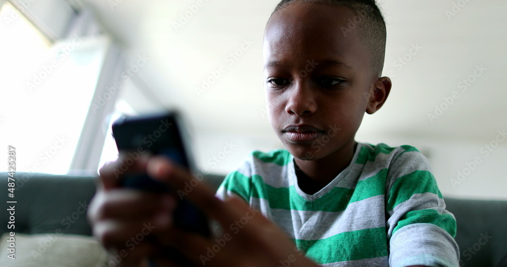 African child holding smartphone device. Mixed race kid using cellphone ...