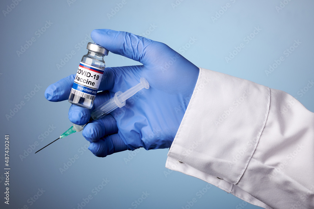 Nurse hand with covid vaccine and syringe. Photo with blue background ...