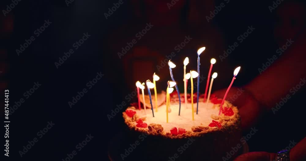 the candle flames on birthday cake lights up in the dark room, family ...