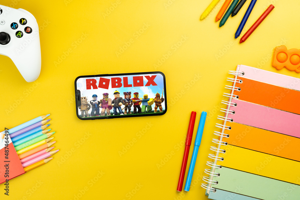 Roblox mobile game app on the smartphone screen. Yellow background with ...