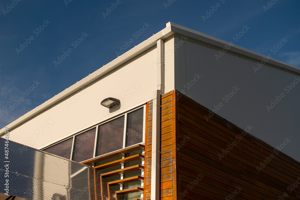 The exterior corner of a brown brick building with tan metal panels on ...