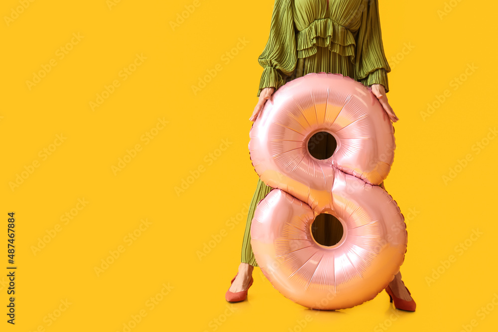 Beautiful woman with big balloon in shape of figure 8 on yellow ...