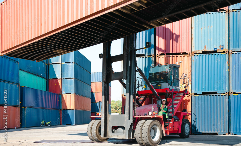 Reach stacker truck lifting heavy cargo box in container yard. Female ...