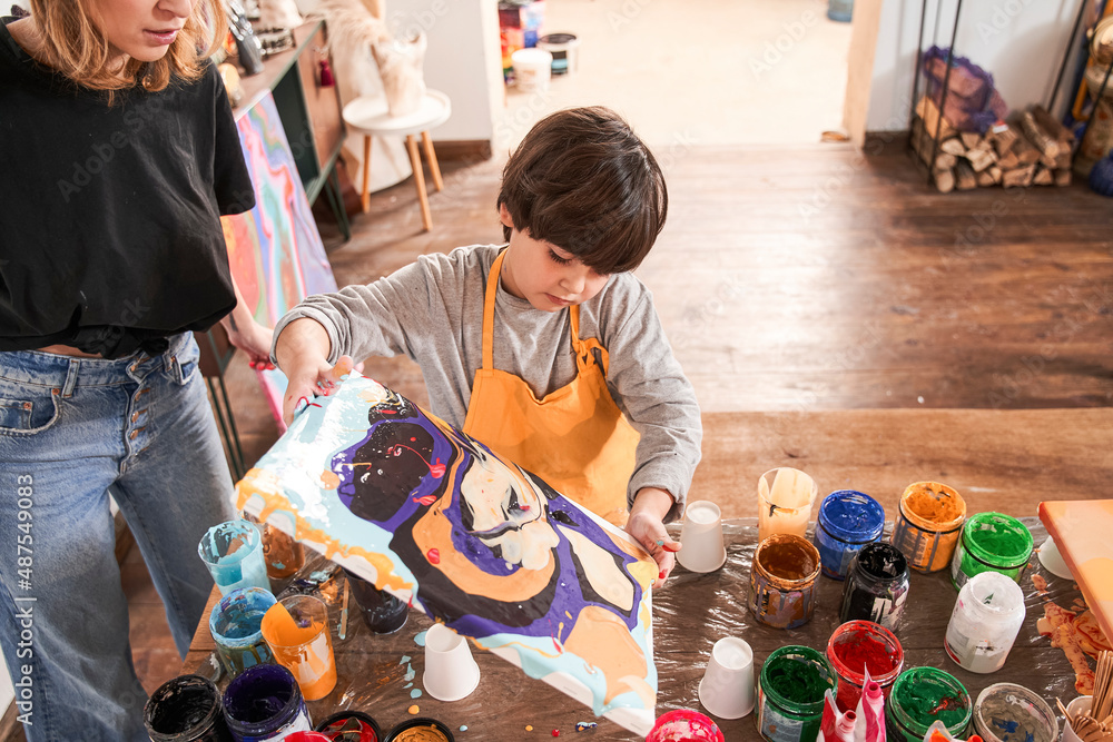 Little boy holding abstract painting executed in fluid art technique ...