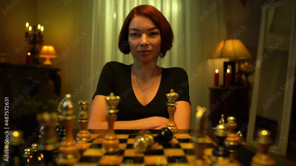Portrait of satisfied redhead woman winning in chess game looking at ...