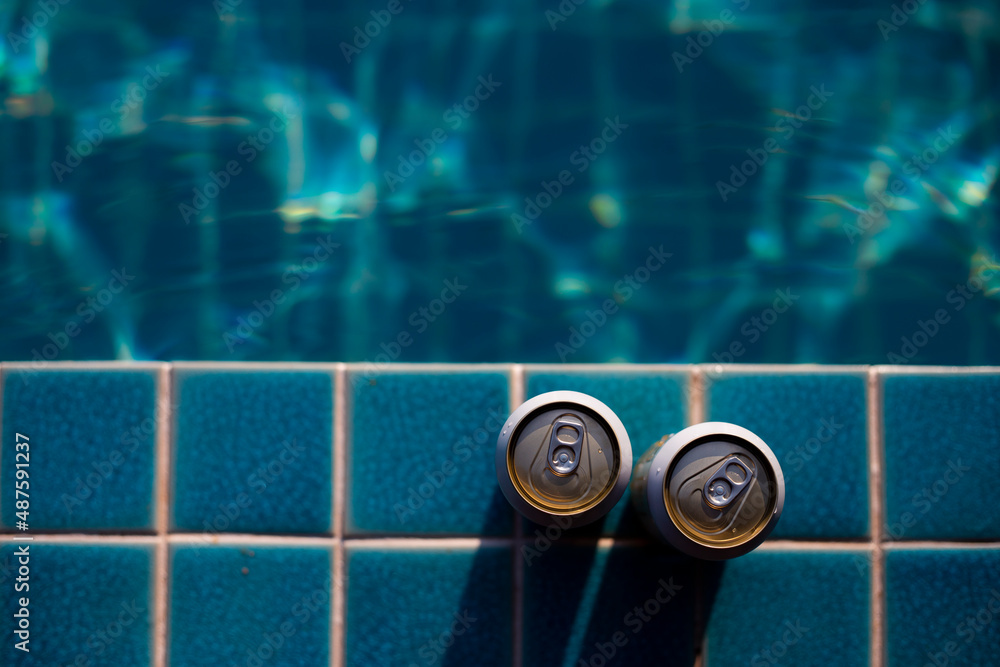 Selective focus Two white beer cans are placed at the edge of the pool ...