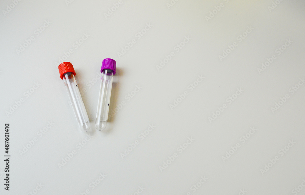 two test tubes with a red and purple cap on a white background. sterile ...