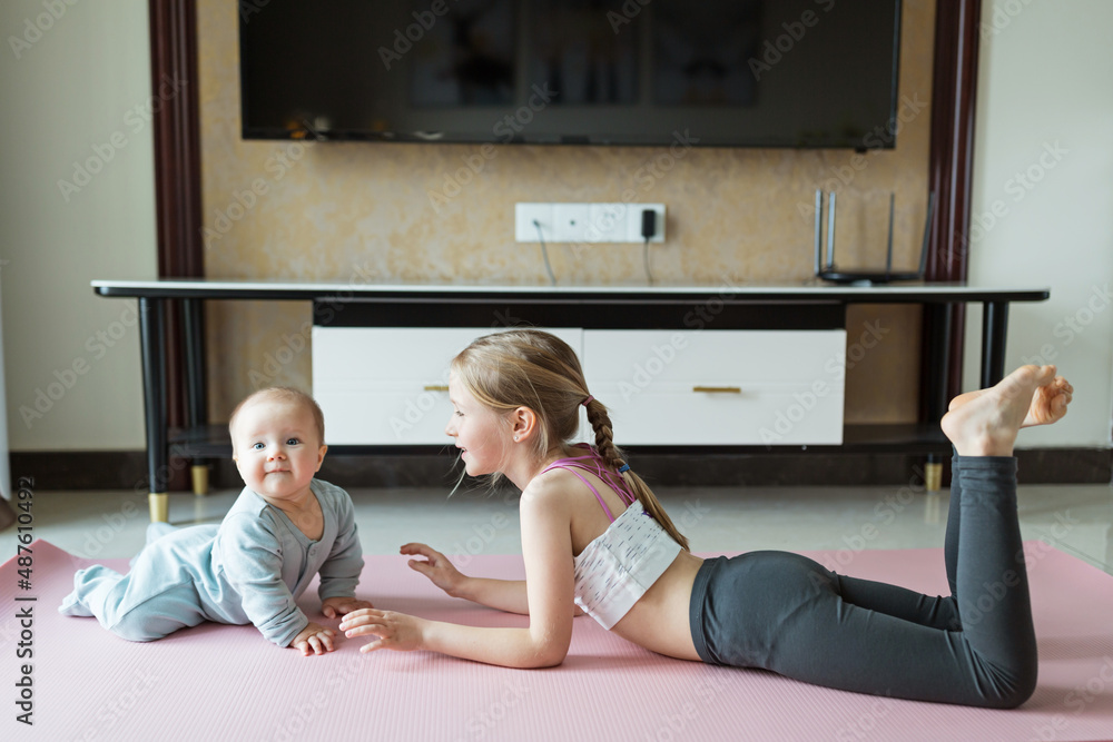 Cute little girl in sportswear doing fitness exercises at home. Distant ...