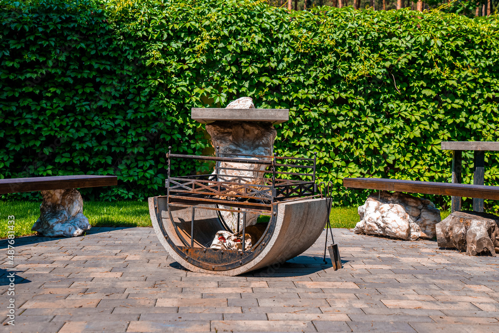 Sunny backyard with iron fire pit and benches on stone pavement, Garden ...