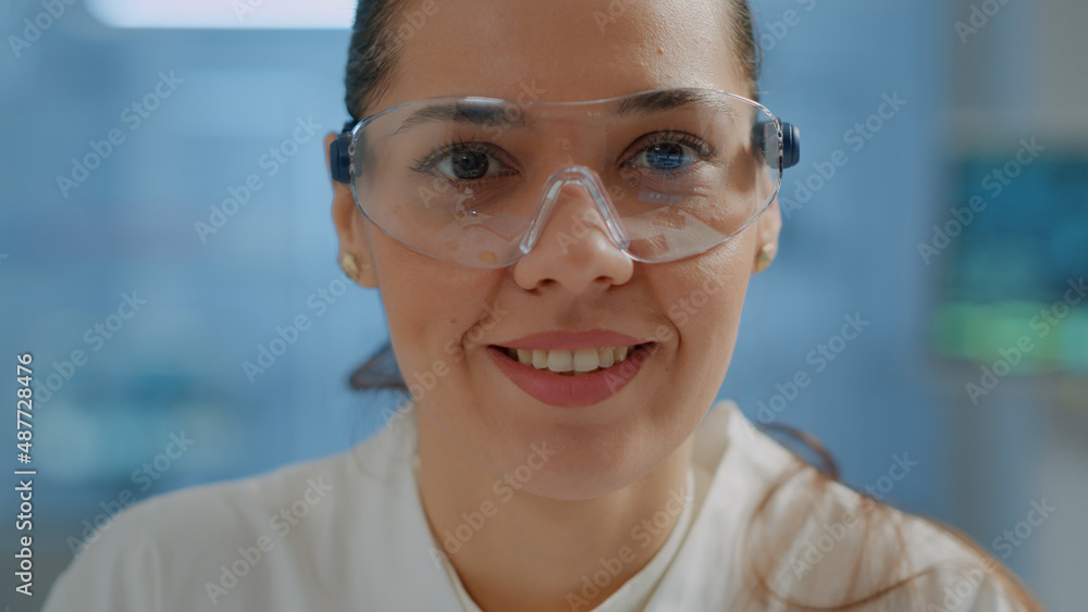 Rack focus of Biologist with safety goggles smiling at camera in ...