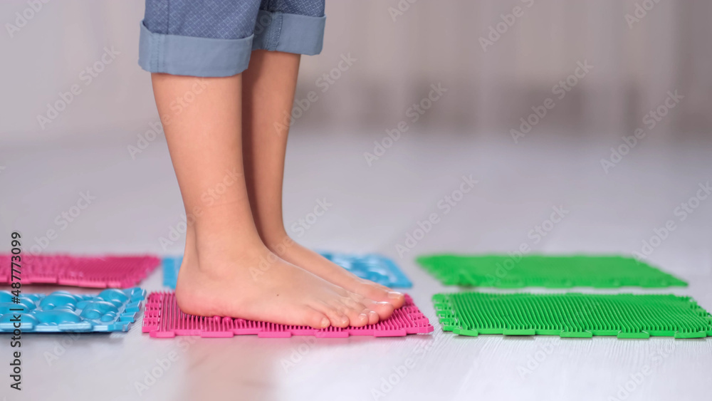 Little boy steps on orthopedic massage mats with different stiffness ...