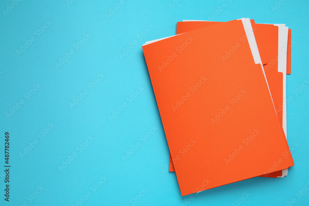 Orange files with documents on turquoise background, top view. Space ...