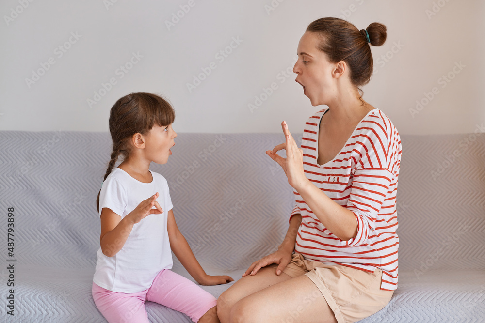 Side view of woman teacher wearing striped shirt and shorts sitting on ...