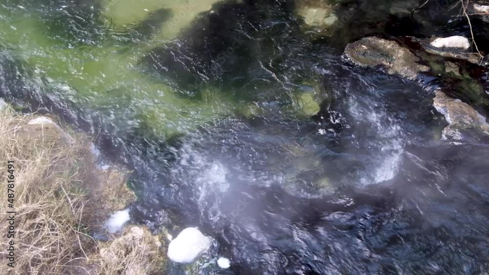 Geothermal hot water stream river with black algae, dry brown fauna ...
