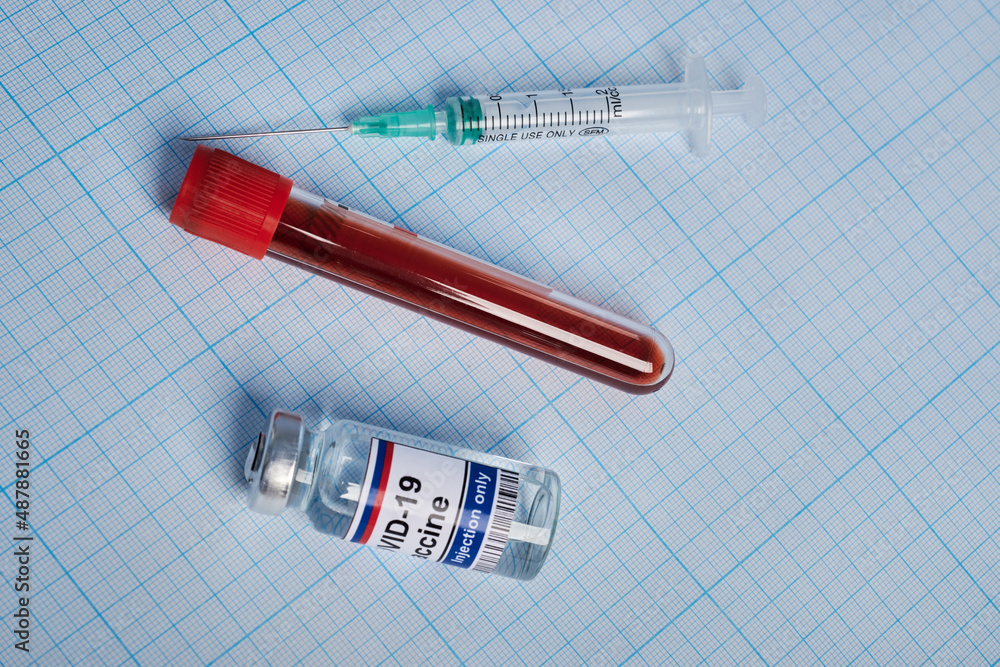 Covid vaccine, blood test-tube, inoculation syringe - photo on a graph ...