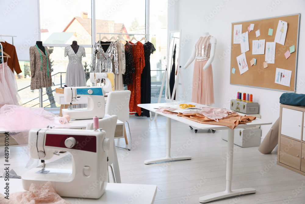 Dressmaking workshop interior with stylish female clothes and equipment ...