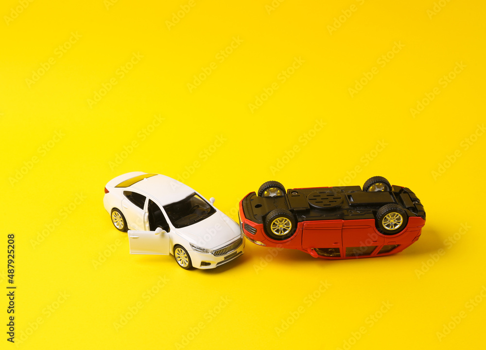 Two mini toy car crash on a yellow background, incident, car traffic ...
