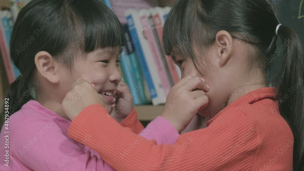 Asian sisters touch each other's cheeks and smile face to face. two ...