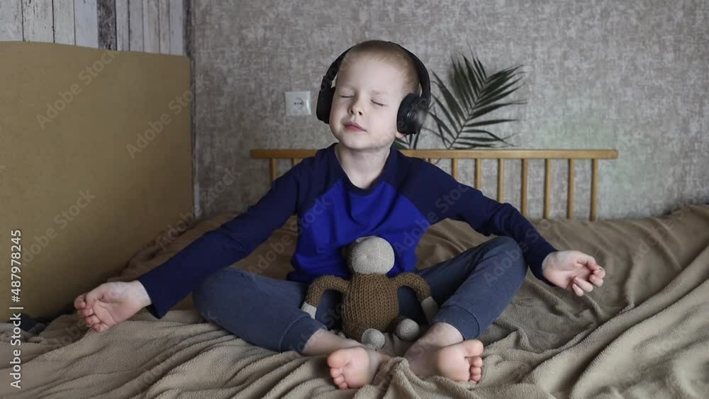 Boy in headphones listens to a meditation for children before going to ...