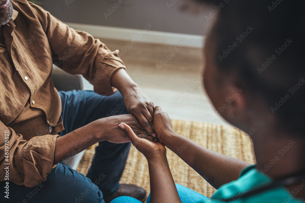 Close-up of home caregiver and senior woman holding hands. Professional ...