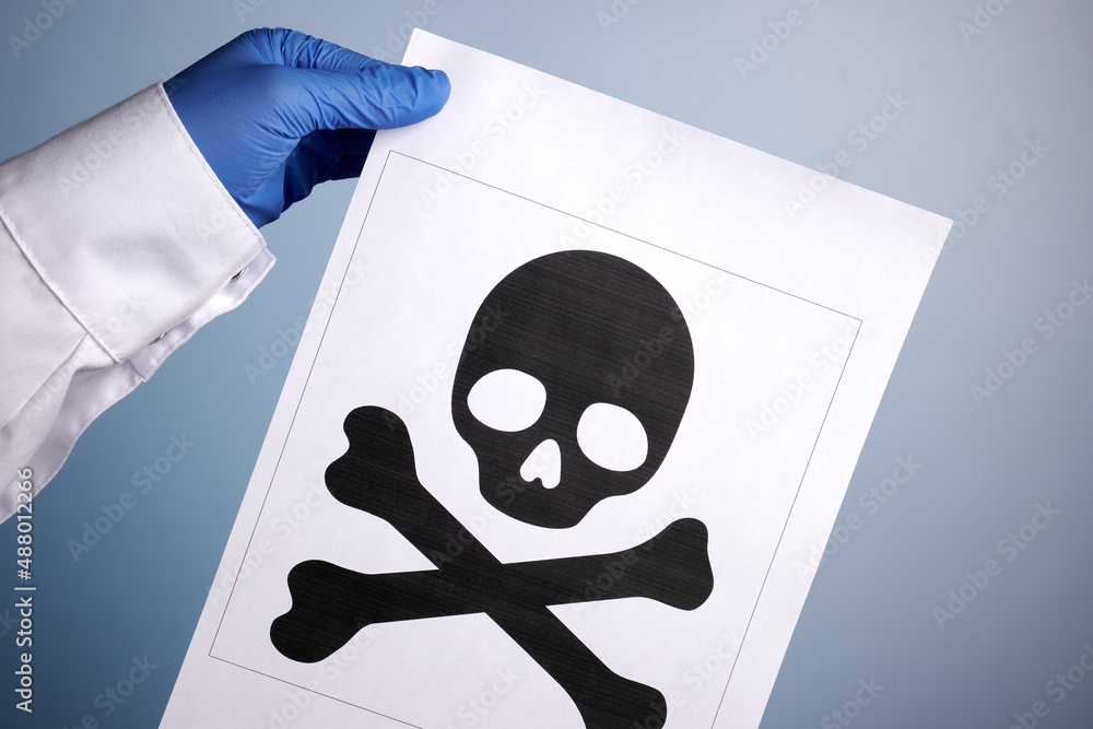 Doctor hand holds death symbol printed on paper page. Black skull with ...