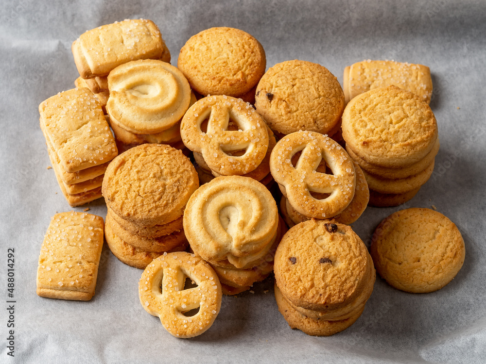 Stacked crispy butter biscuits on a white baking parchment. Variety of ...