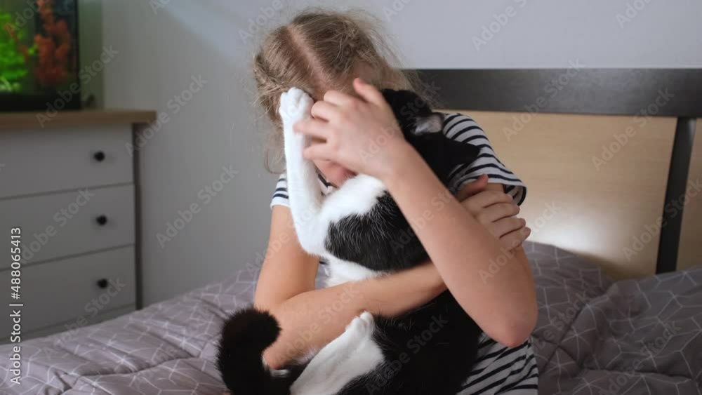 Teenage Girl hugging and kissing black and white cat. Cat scratching ...