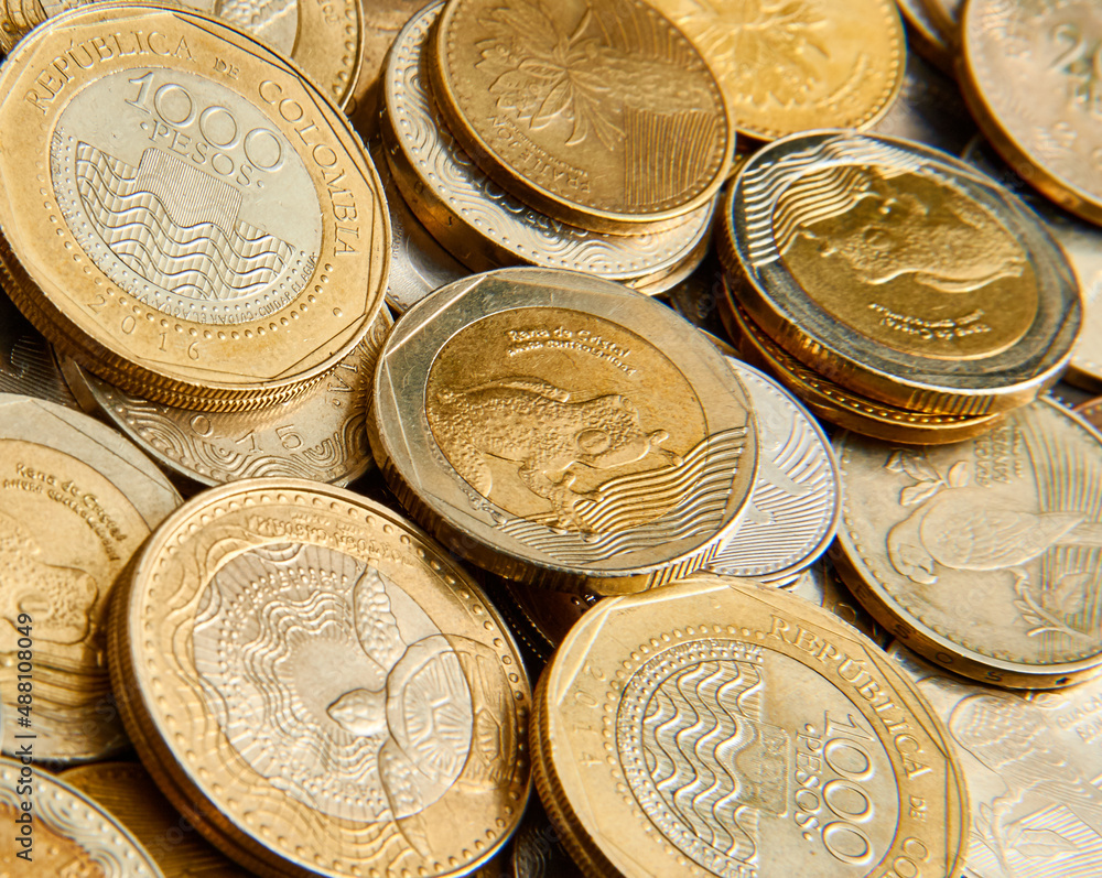 muchas monedas colombianas de 500 pesos y 1000 pesos sobre una mesa ...