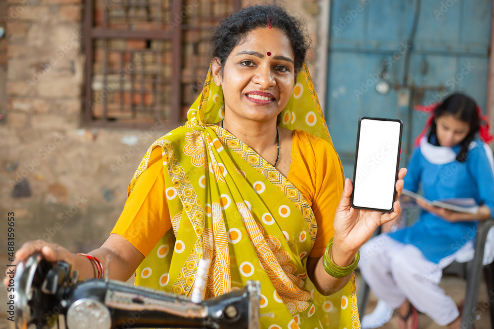 Portrait of happy traditional indian woman wearing sari using sewing ...
