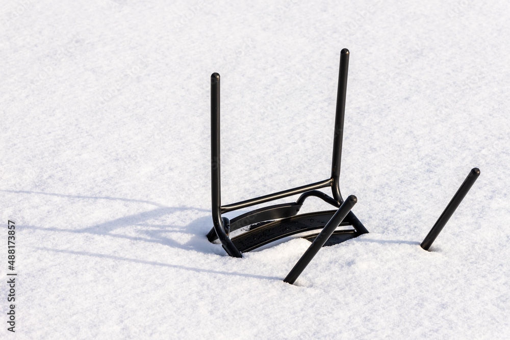 Frozen discarded chair upside down is frozen into ice on the lake ...