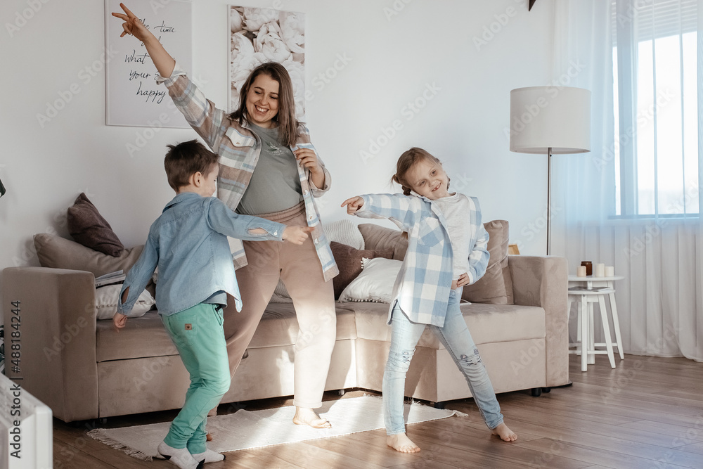 Mom dances with her kids at home. The kids and mom are laughing. A ...
