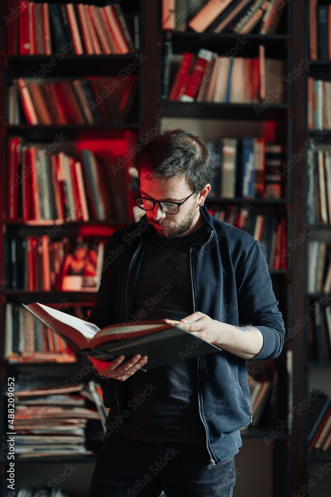 Adult student reading a book in the college library in a red light ...