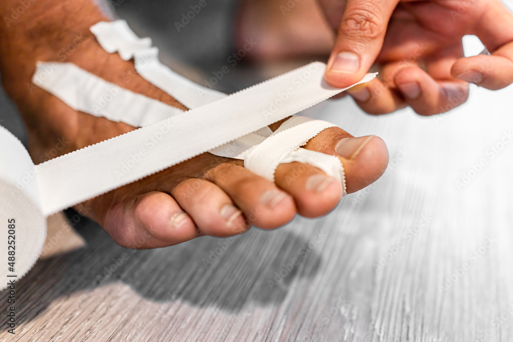 Closeup of young man body part leg feet on wooden floor taping fingers ...