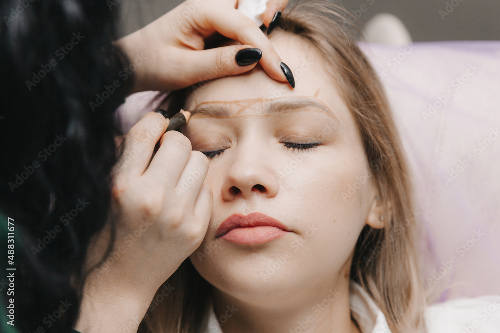 girl with permanent makeup on her eyebrows. The makeup artist makes ...