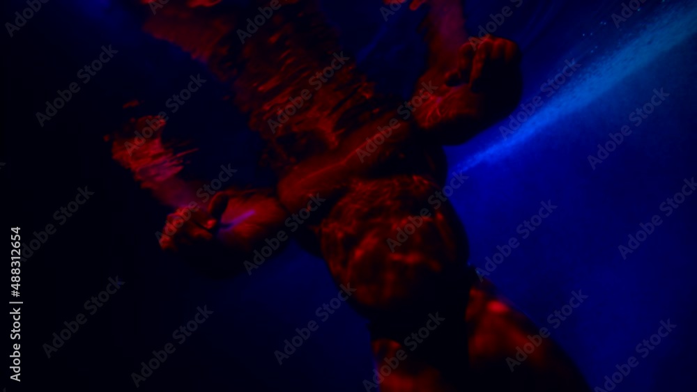 brawny swimmer is floating in pool, underwater shot on muscular body ...